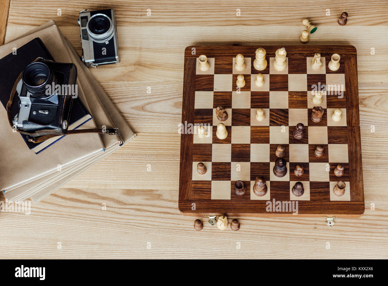 Above view of chess board set with old vintage cameras and books on ...
