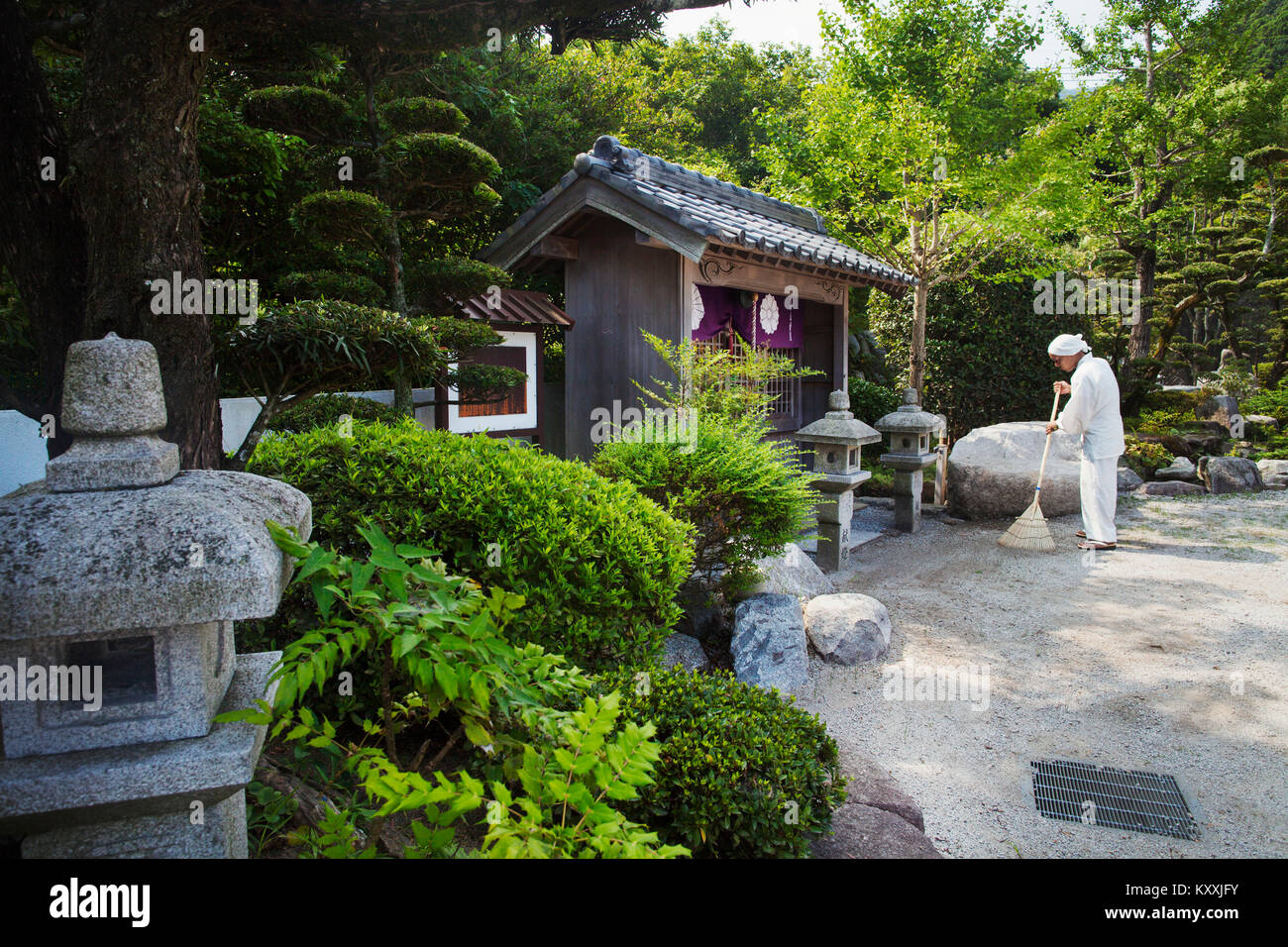 Buddhist monk wearing white robe and cap standing outside a shrine in a ...