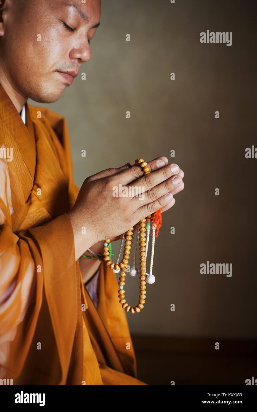Side view of Buddhist monk with shaved head wearing golden robe ...