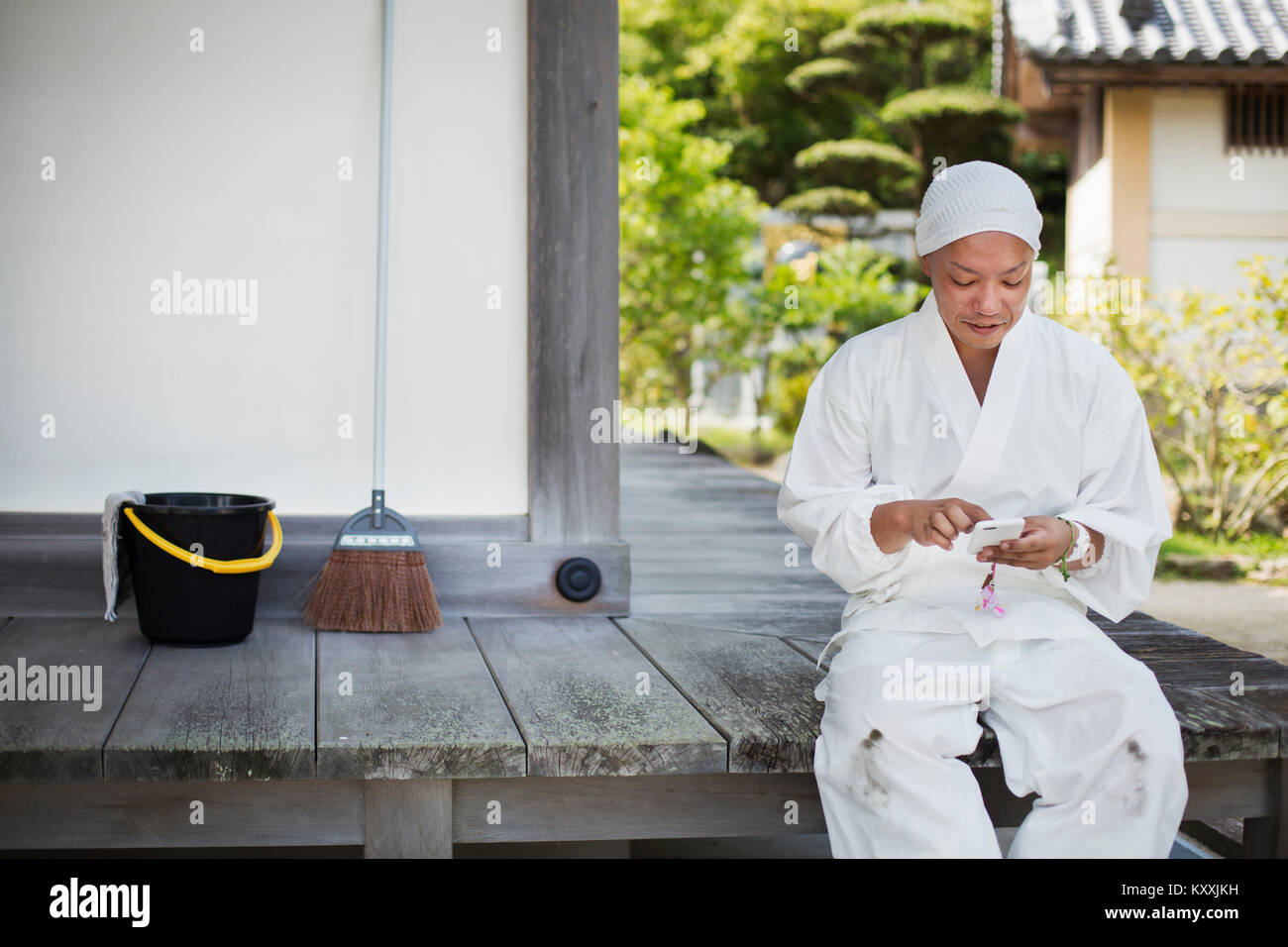 Buddhist monk wearing white robe and cap sitting on wooden floor ...