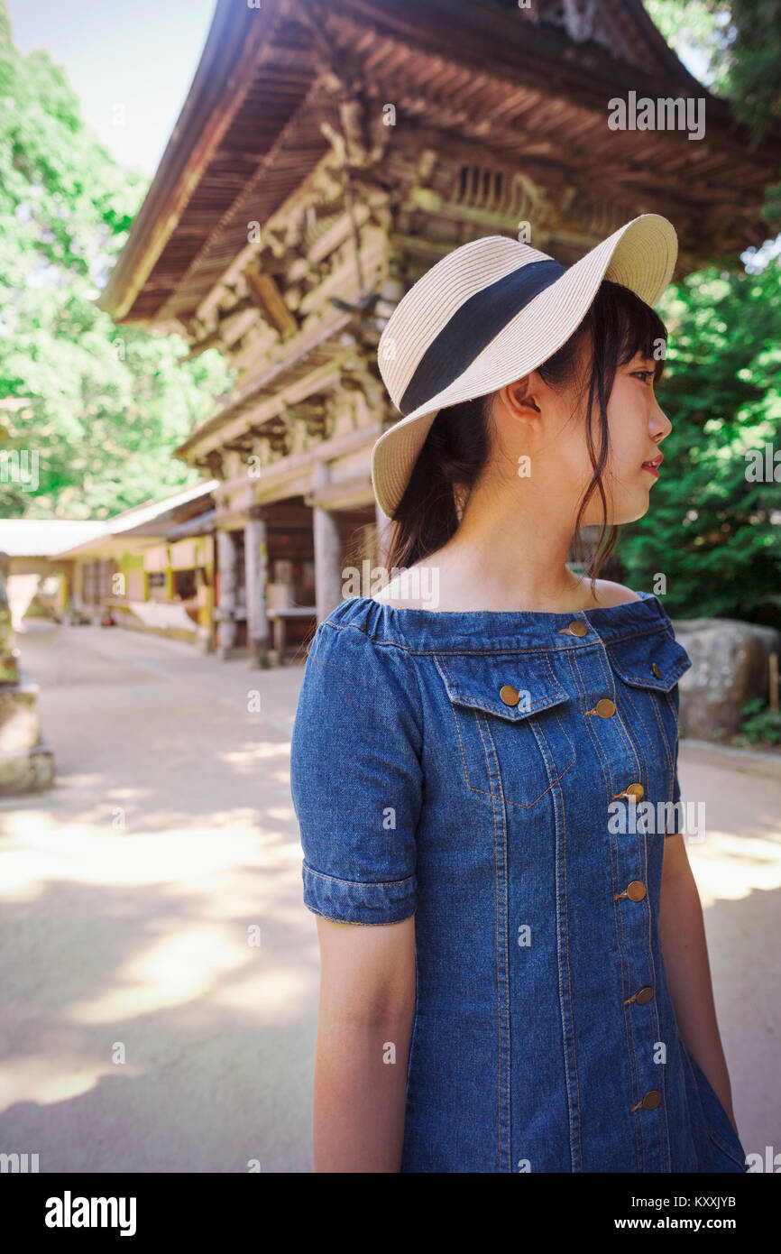 Young woman wearing blue dress and hat standing at Shinto Sakurai ...
