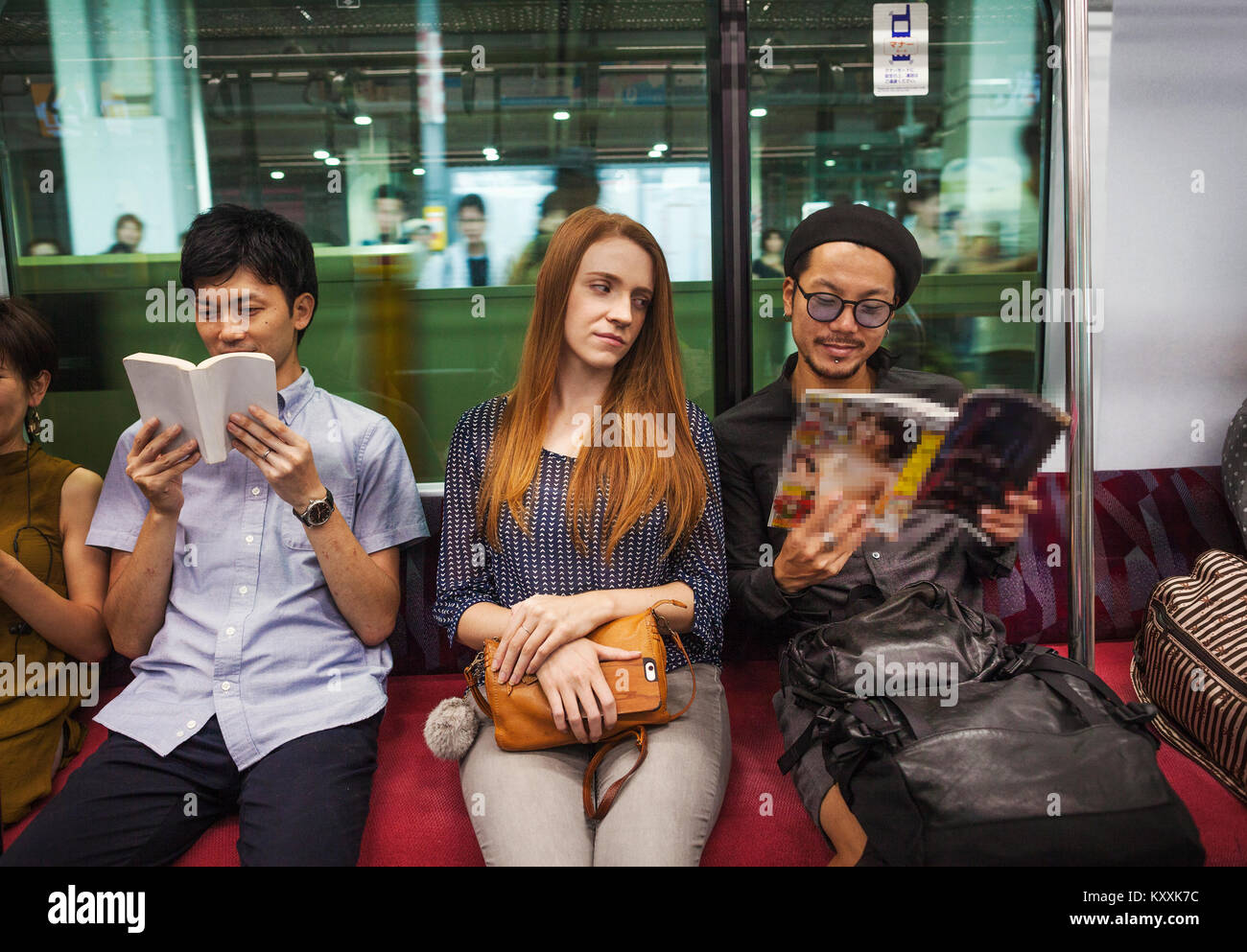 Three people sitting sidy by side on a subway train, reading,Tokyo ...