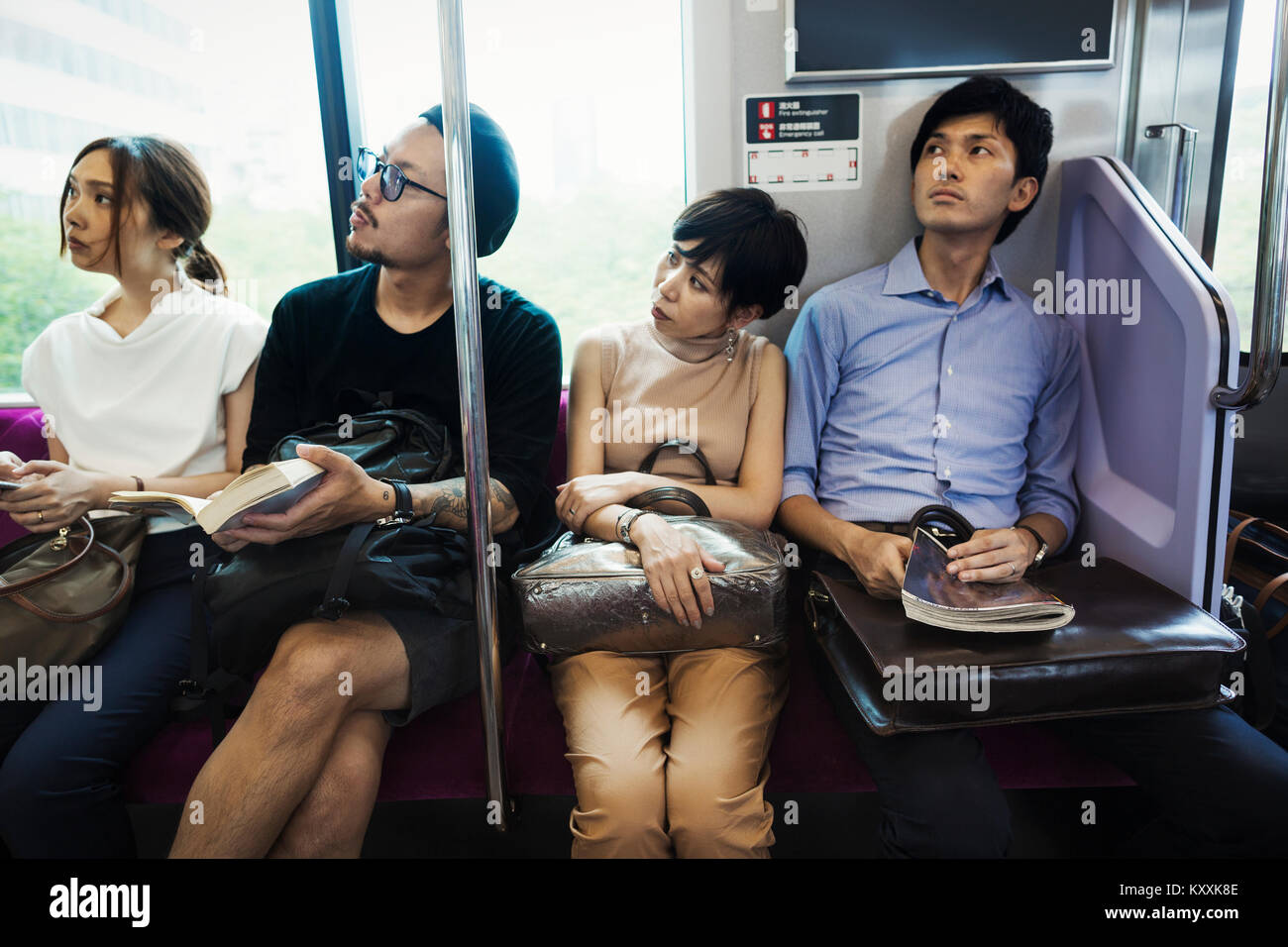 Four people sitting sidy by side on a subway train, Tokyo commuters ...