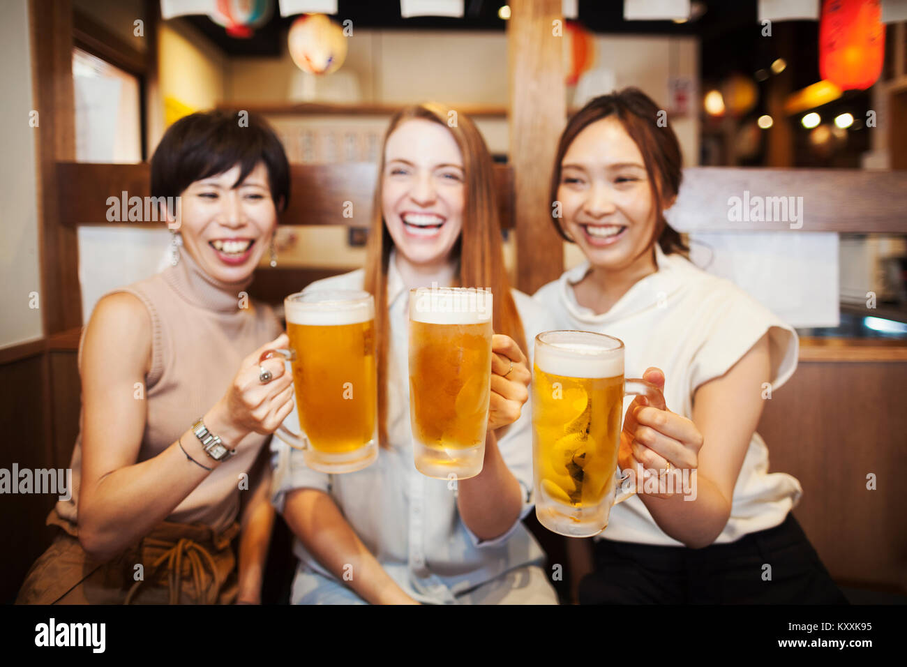 Three women sitting sidy by side at a table in a restaurant, holding ...