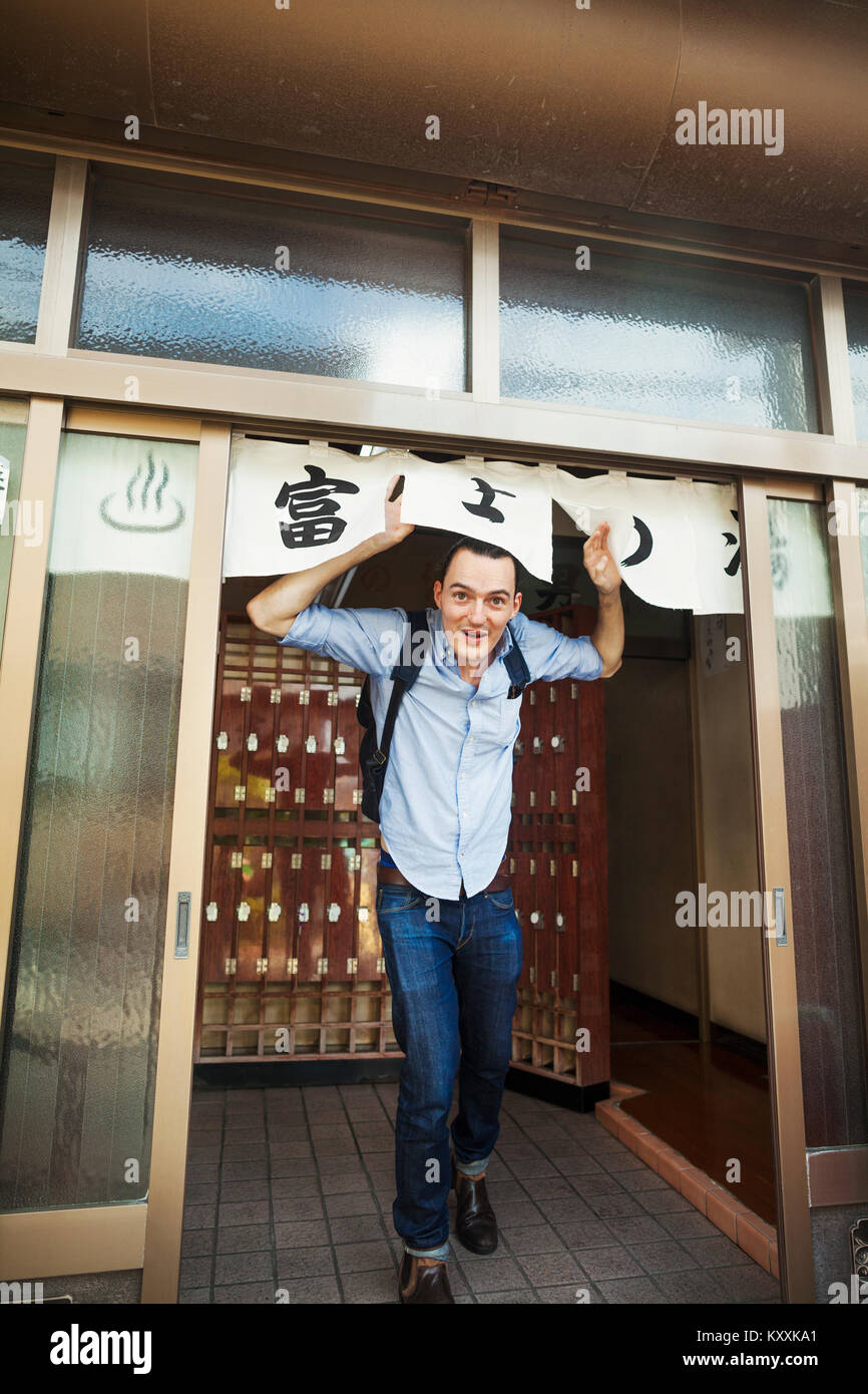 A young Western man coming out of a public bath house, ducking under ...
