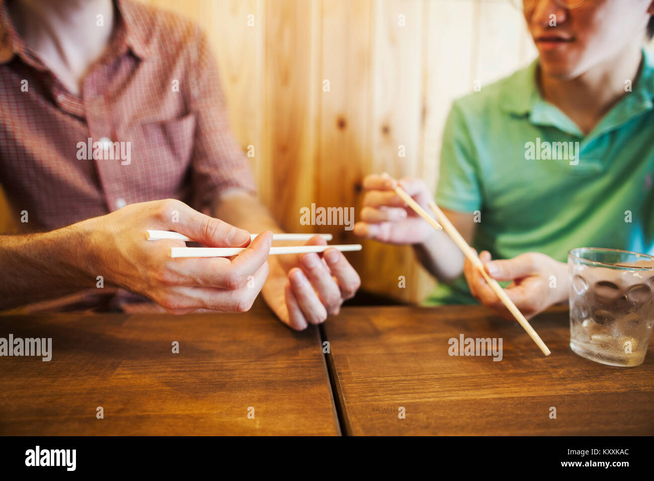 Two people, a Japanese man showing a Western man how to use chopsticks ...