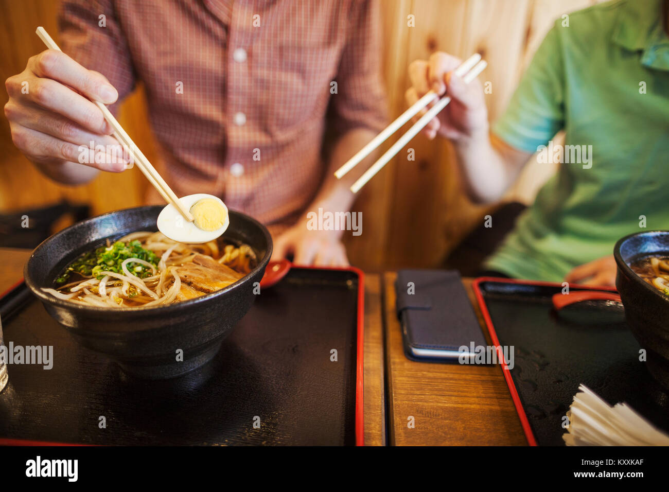Two people, a Japanese man showing a Western man how to use chopsticks ...