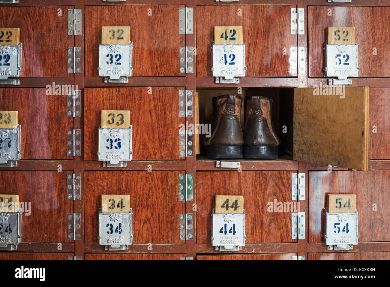 One pair of shoes in a shoe locker with an open door. Lockers in a row ...