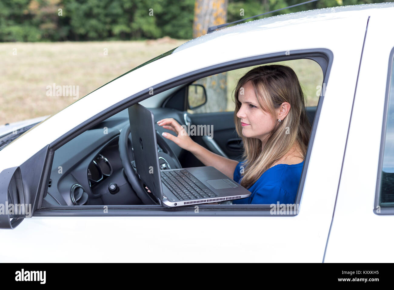 Young woman using laptop in her car. Safe driving concept Stock Photo ...
