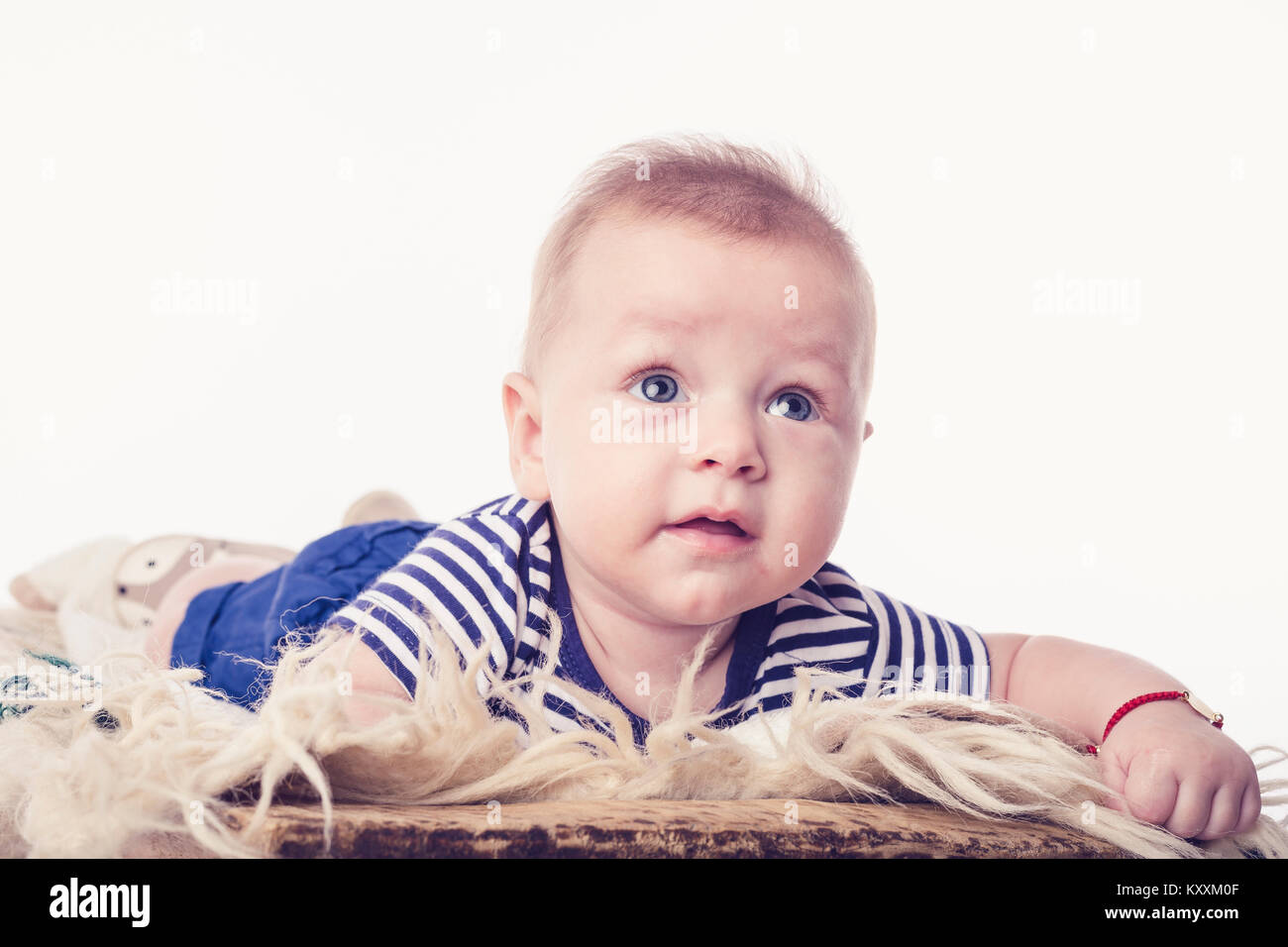 Adorable baby boy with big blue ayes lying on the bed over white ...