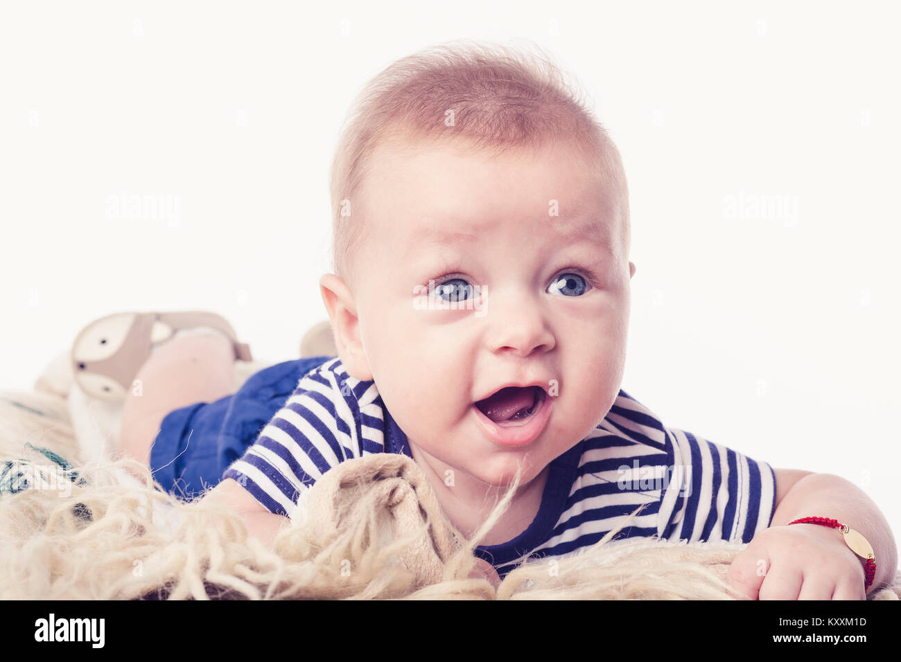 Adorable baby boy with big blue ayes lying on the bed over white ...