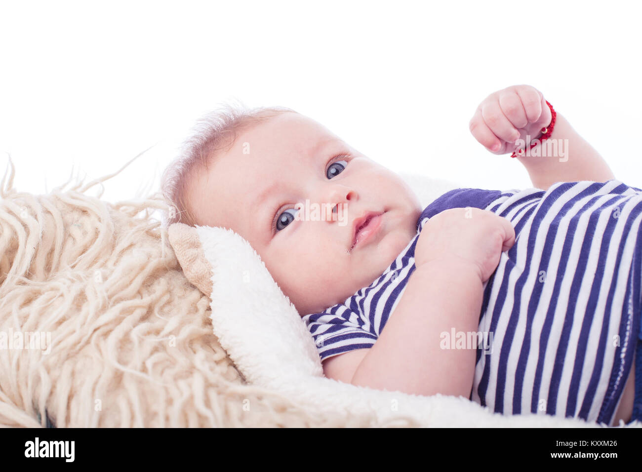 Adorable baby boy with big blue ayes lying on the bed over white ...