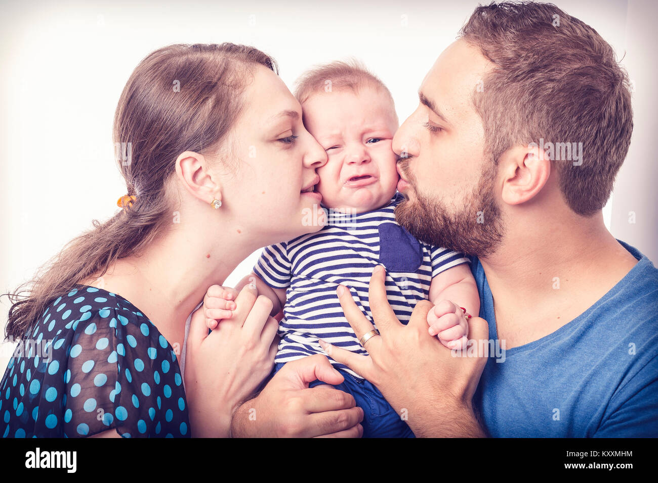 Two loving parents kissing their baby boy over white Stock Photo - Alamy