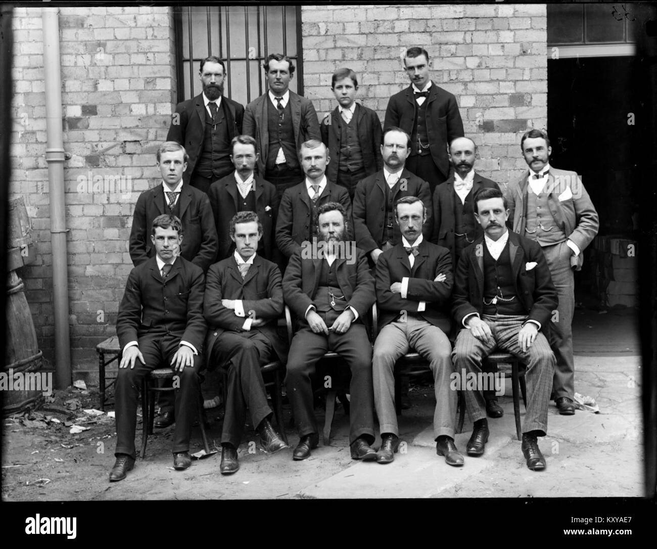 Historical photograph depicting fifteen men standing before a large ...