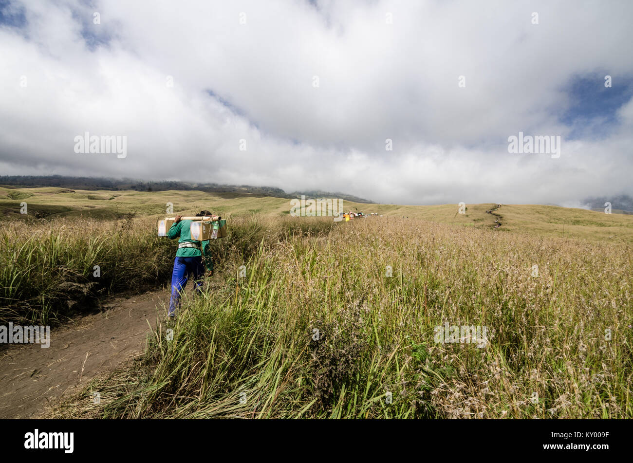 Porter of Mount. Rinjani helping hiker to carry stuff. The mountain is ...