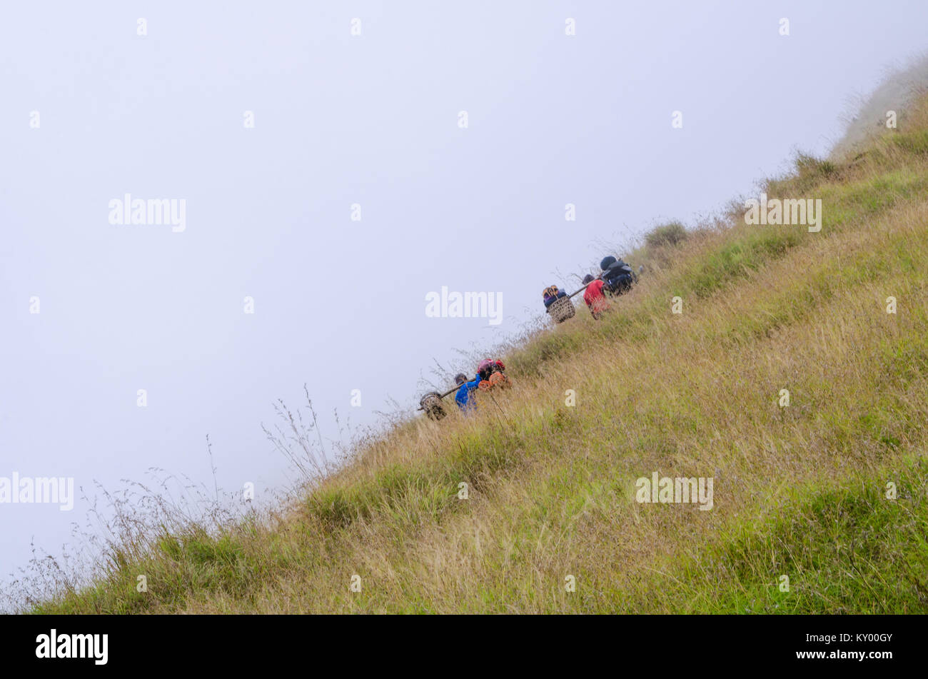 Porter of Mount. Rinjani helping hiker to carry stuff. The mountain is ...