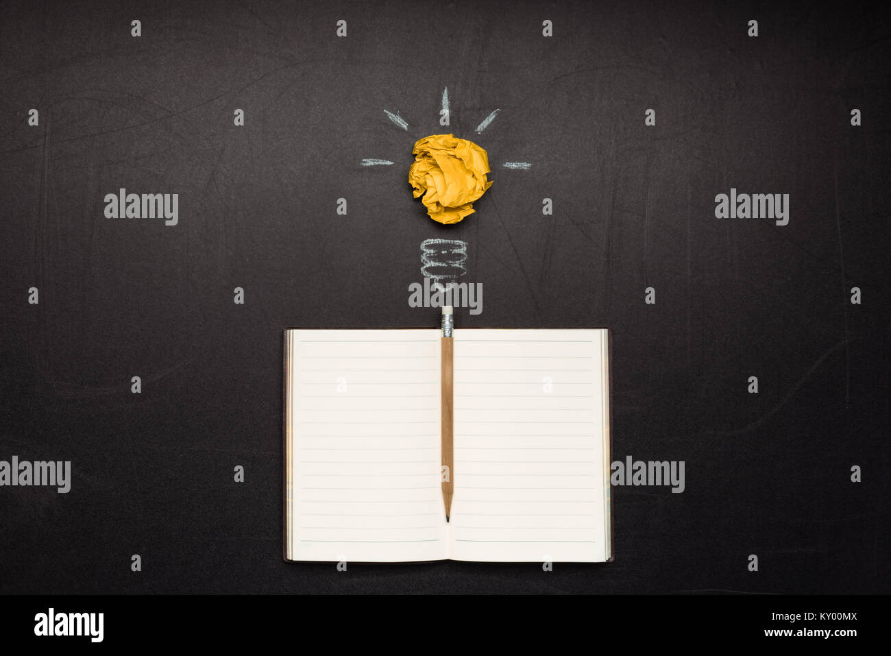 light bulb symbol and blank notebook with pencil on blackboard Stock ...