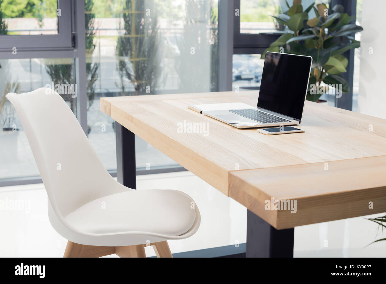 side view of laptop, smartphone and blank papers on workplace in empty ...
