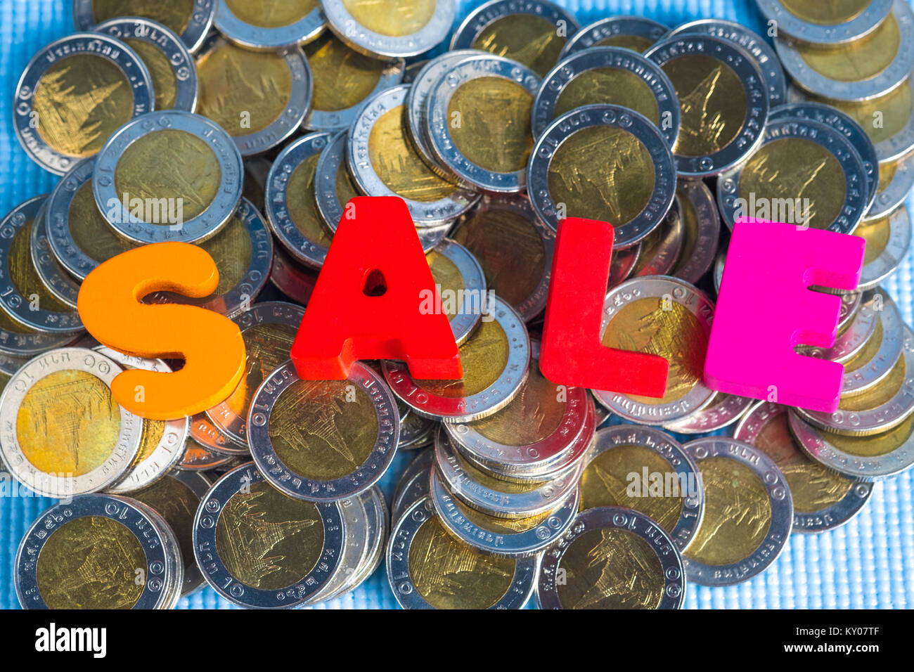 Sale colorful wooden text with coin stack on blue background with copy ...