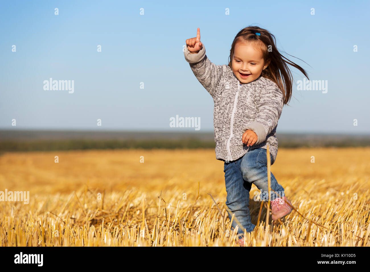 Happy 2 year old girl walking in a summer harvested field Stock Photo ...
