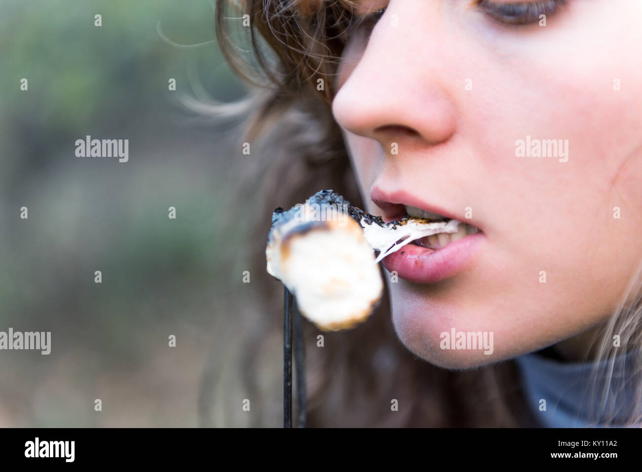 Young woman eating roasted caramelized marshmallow skewer closeup macro ... Young woman eating roasted caramelized marshmallow skewer closeup macro ...