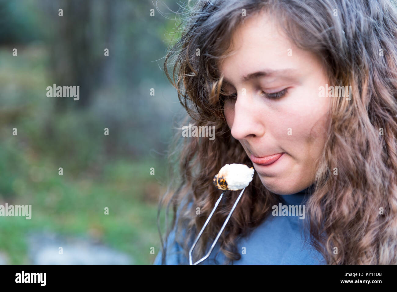 Young woman eating roasted caramelized marshmallow skewer closeup macro ... Young woman eating roasted caramelized marshmallow skewer closeup macro ...