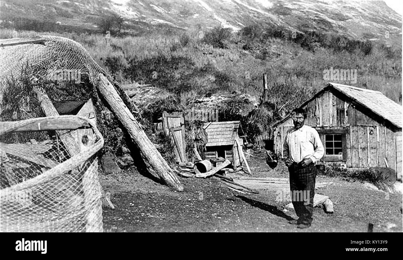 This photograph depicts an Eskimo standing in front of traditional ...