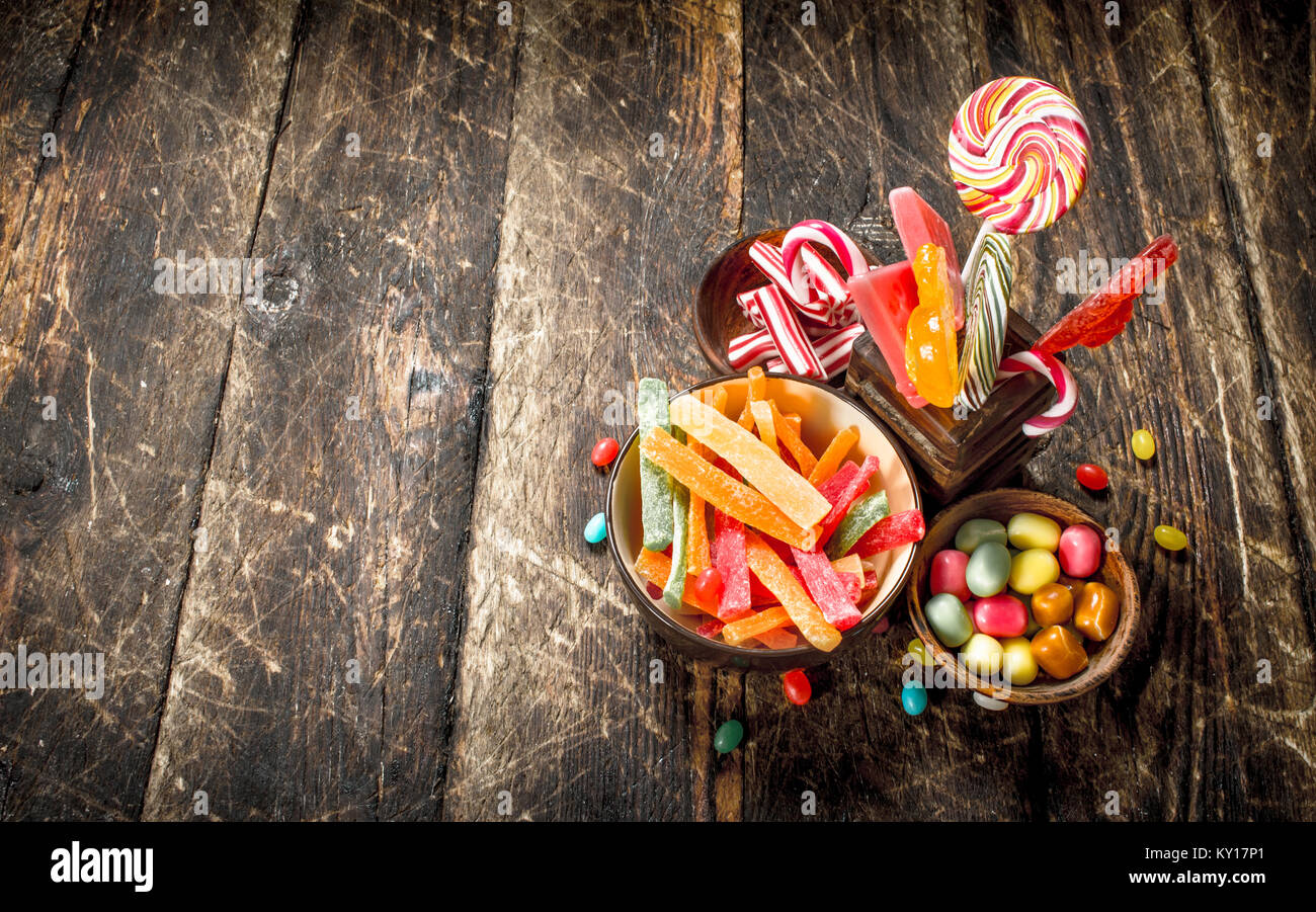 Different sweet candy in bowls. On a wooden background Stock Photo - Alamy