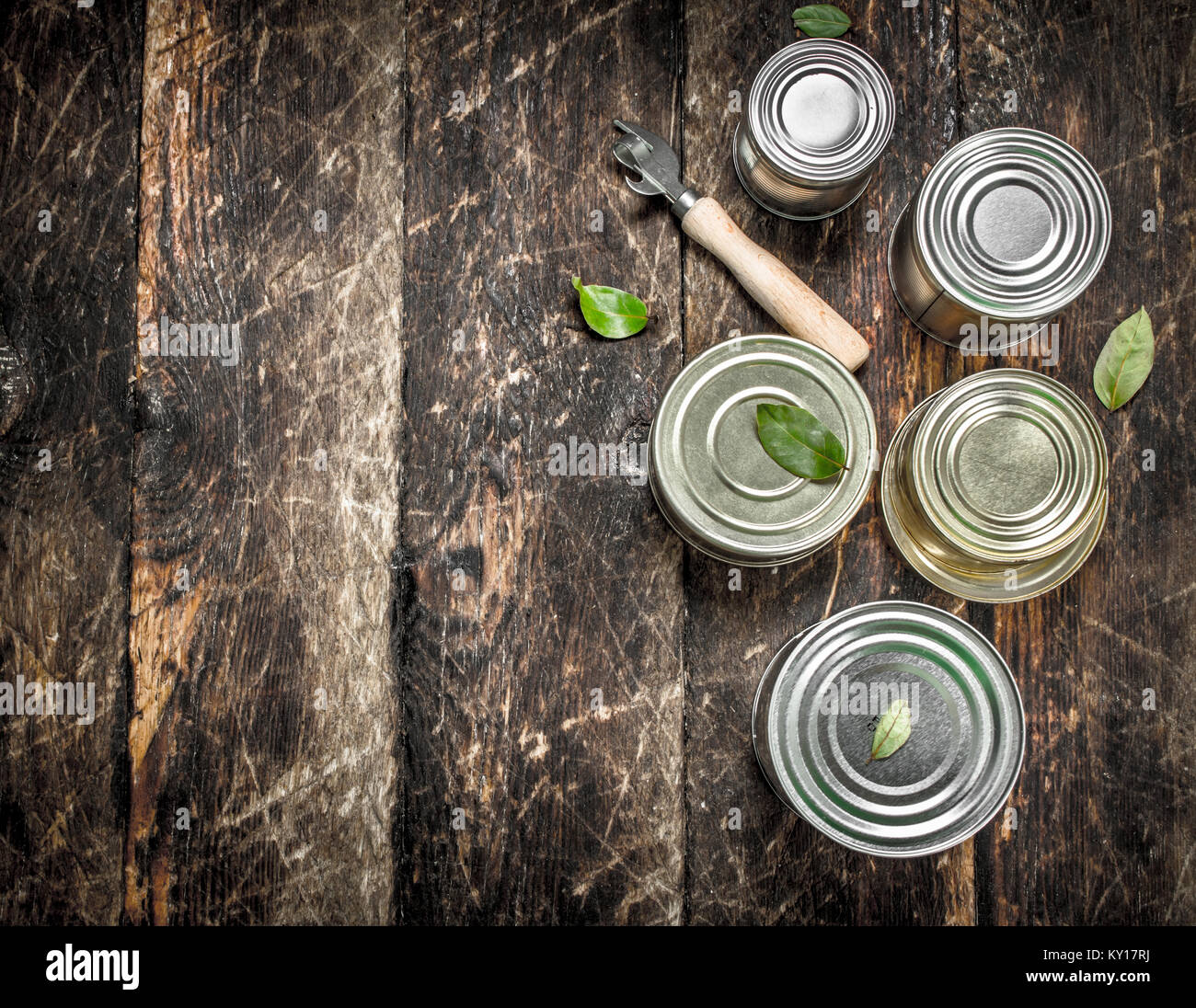 Food in tin cans with opener. On a wooden background Stock Photo - Alamy