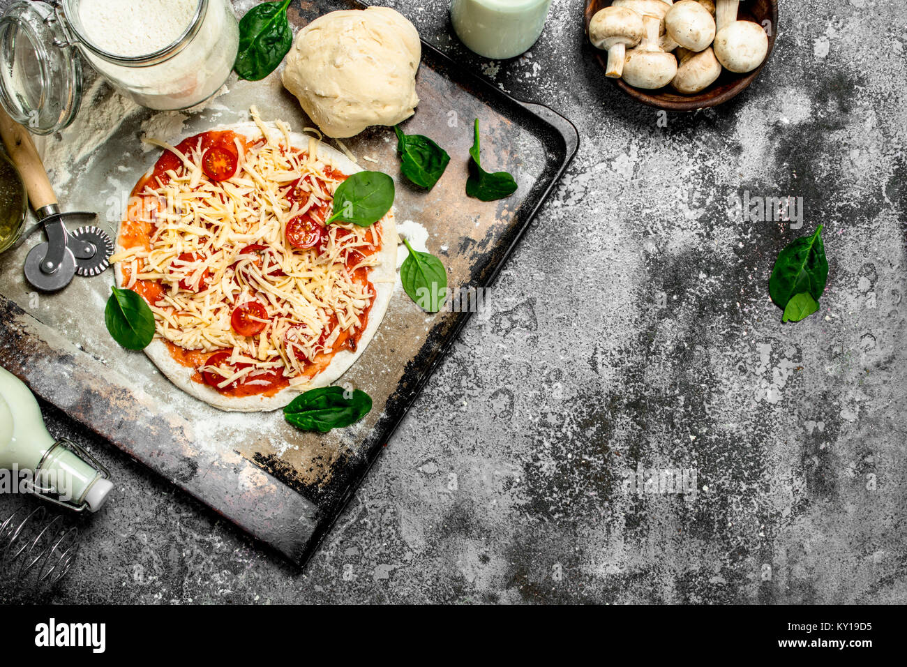 Unprepared pizza with ingredients. On a rustic background Stock Photo ...