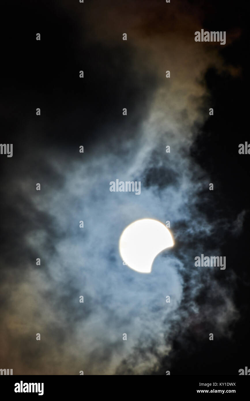 Start of full solar eclipse on cloudy sky background Stock Photo - Alamy