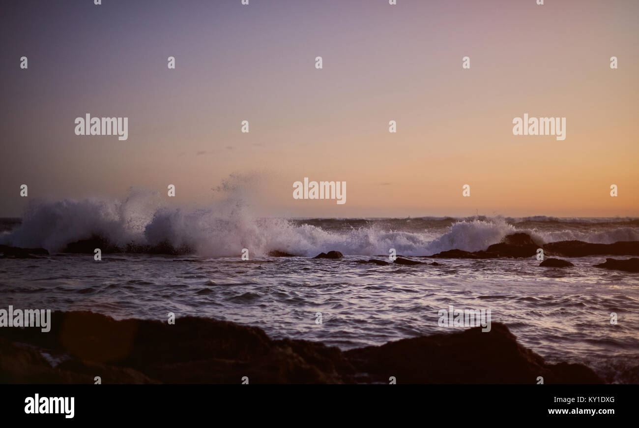 Panorama of seascape in sunset time. Waves crash on rocks at ocean dusk ...