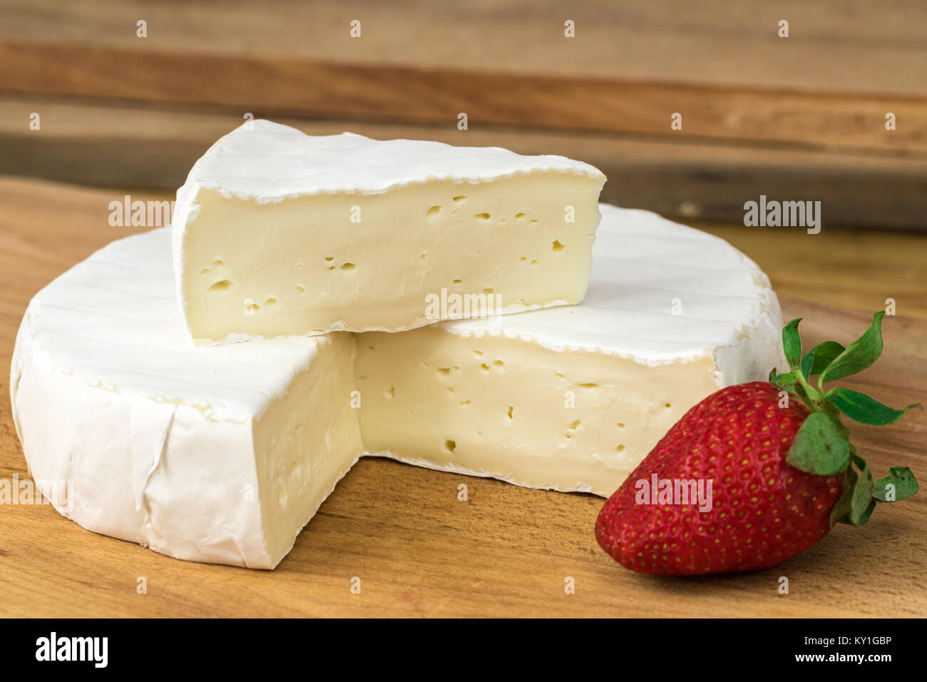 Wheel of Camembert cheese brie with triangle cut out and strawberry ...