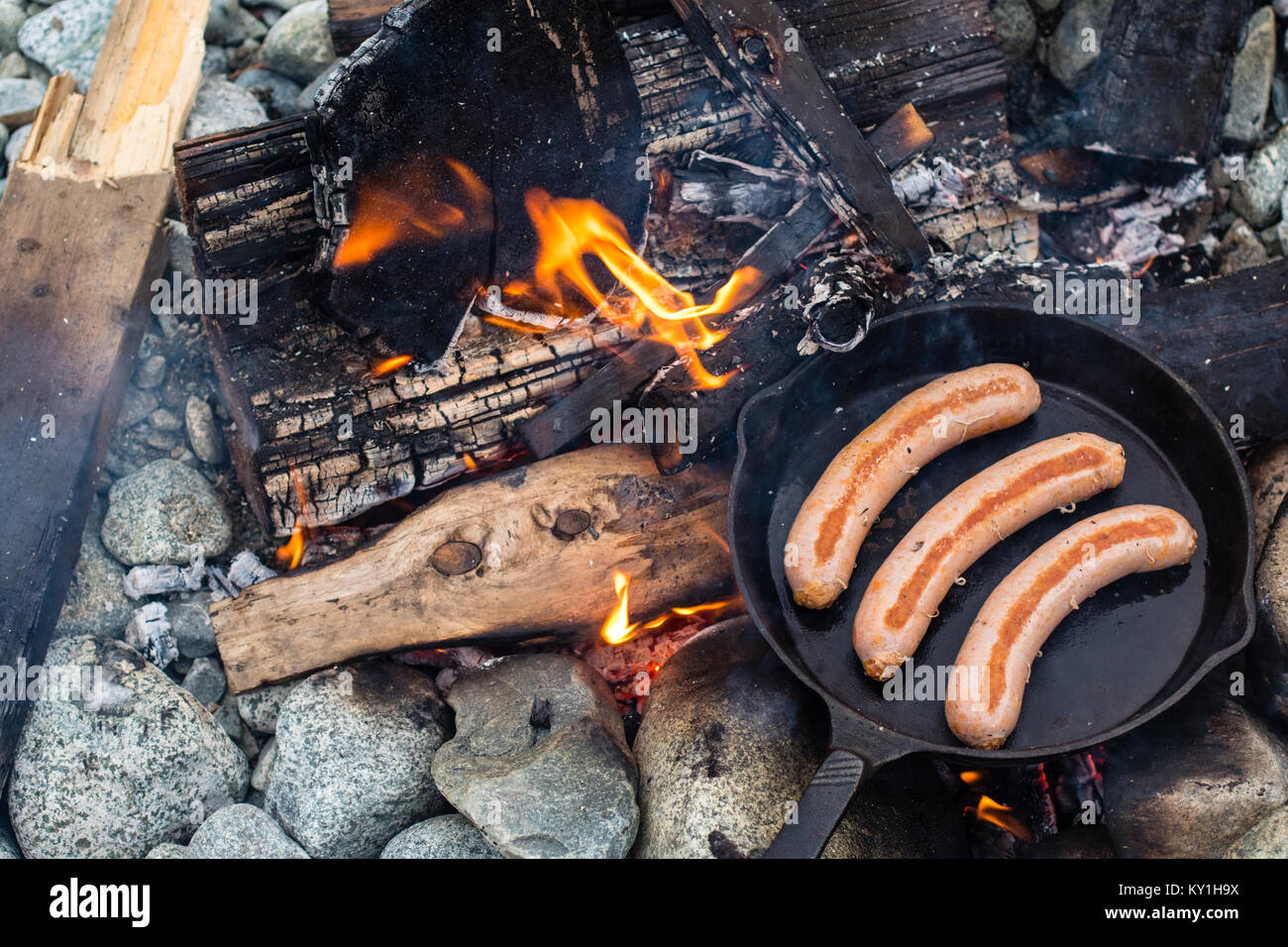 Live fire cooking juicy sausages over campfire Stock Photo - Alamy