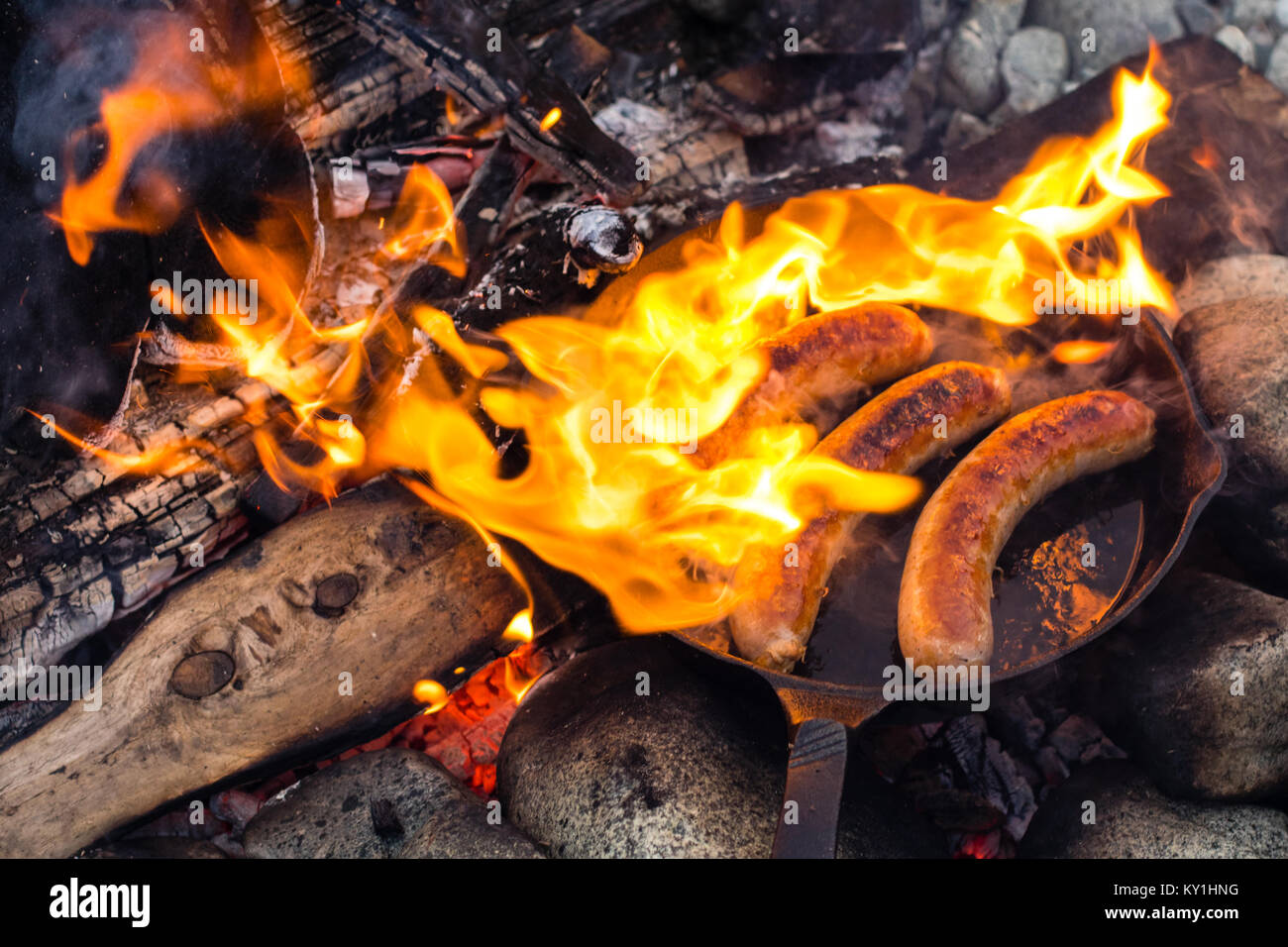 Live fire cooking juicy sausages over campfire Stock Photo - Alamy