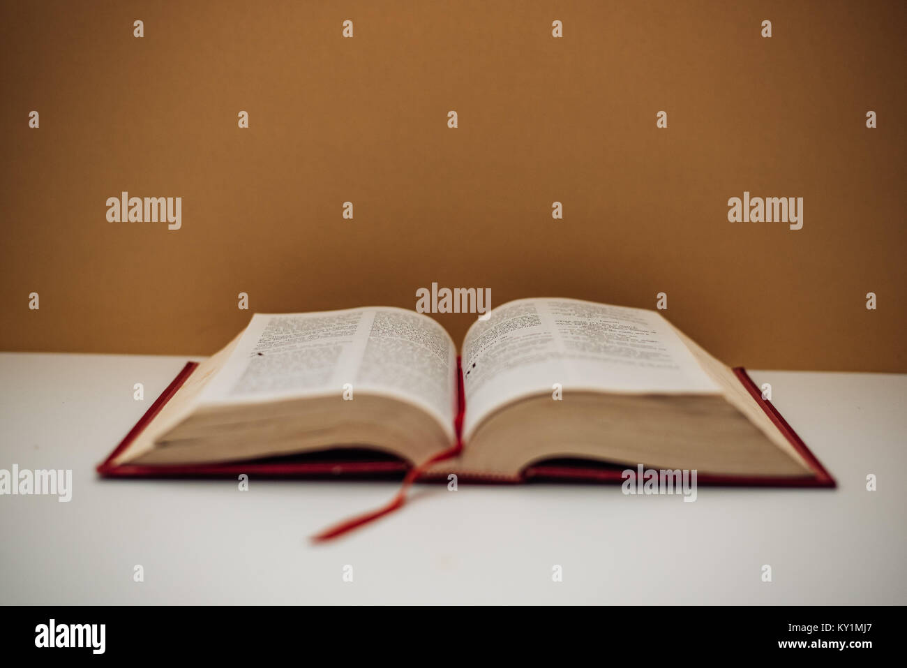 A bible laying open on a table with a yellow background Stock Photo - Alamy