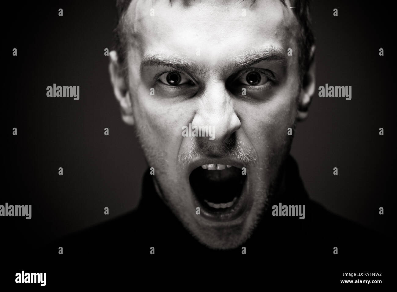 Angry man screaming. A man in a black shirt Stock Photo - Alamy