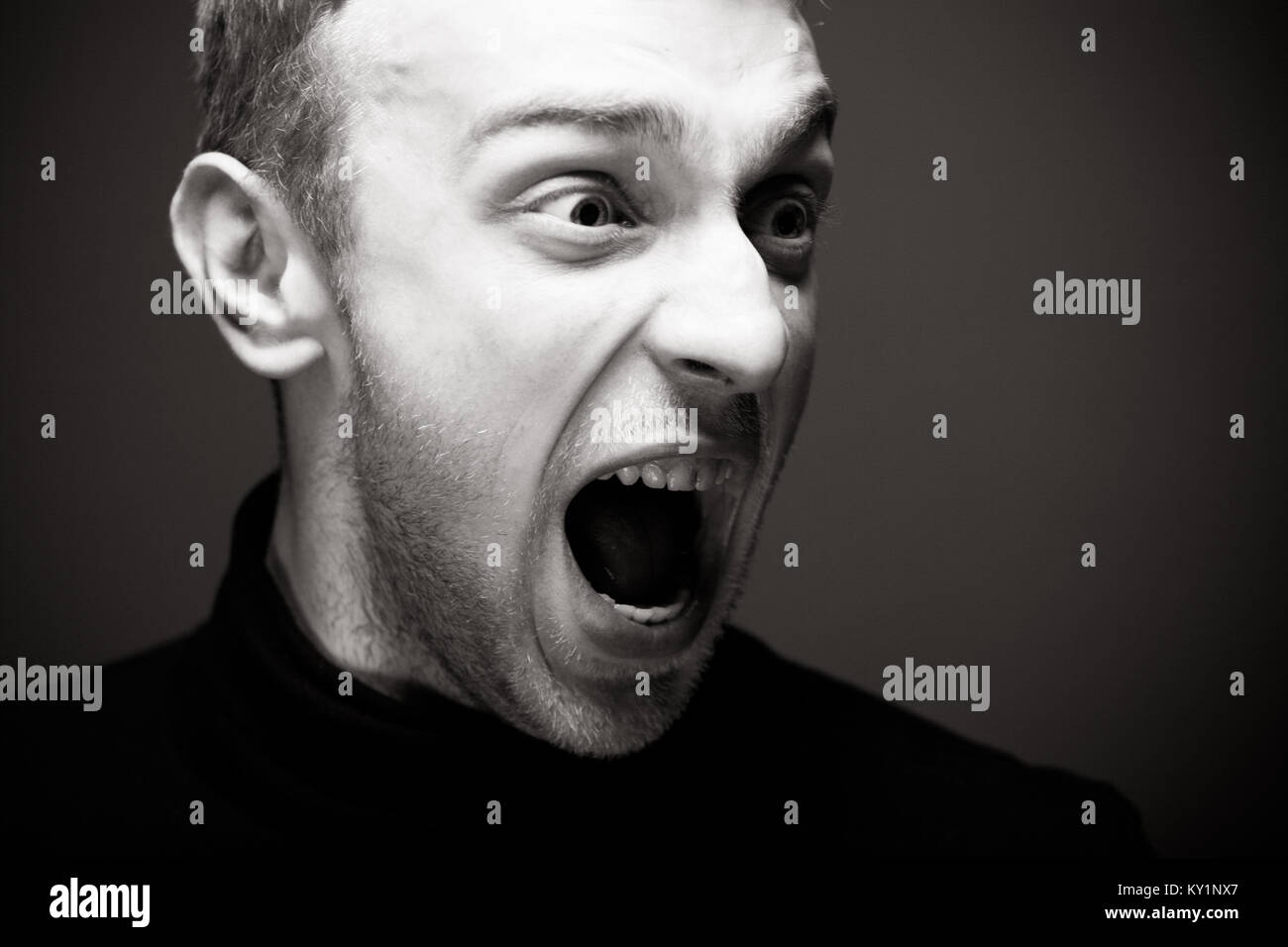 Angry man screaming. A man in a black shirt Stock Photo - Alamy