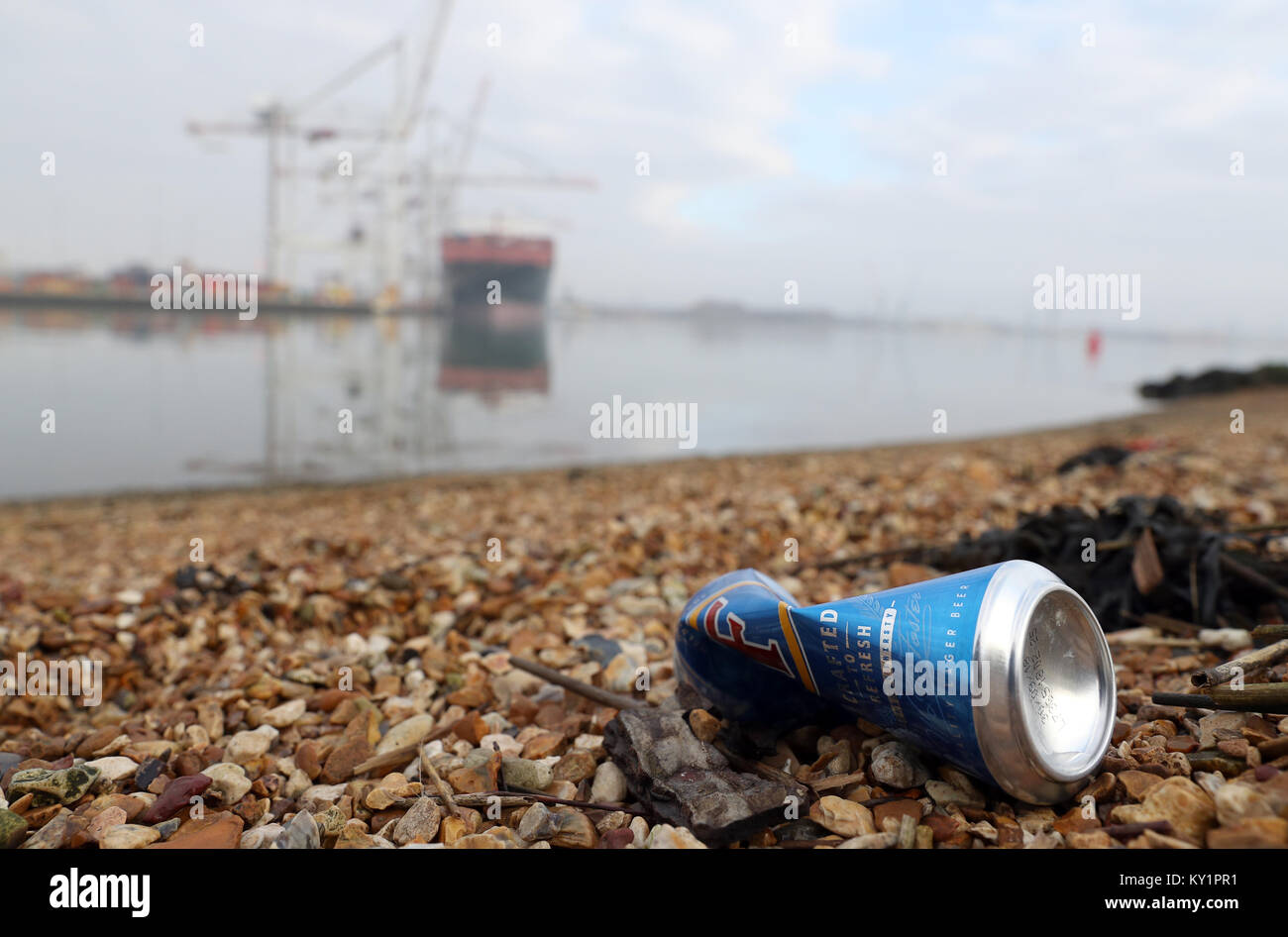 A discarded Fosters beer can on a shingle beach opposite DP World ...