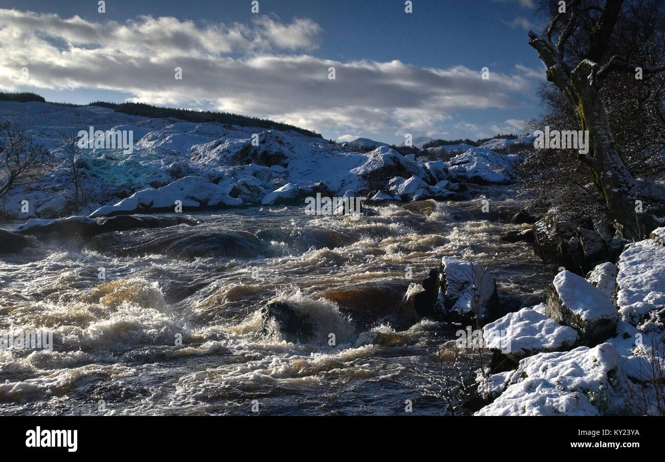 Scottish Highland river in winter spate from snow melt .River runs from ...
