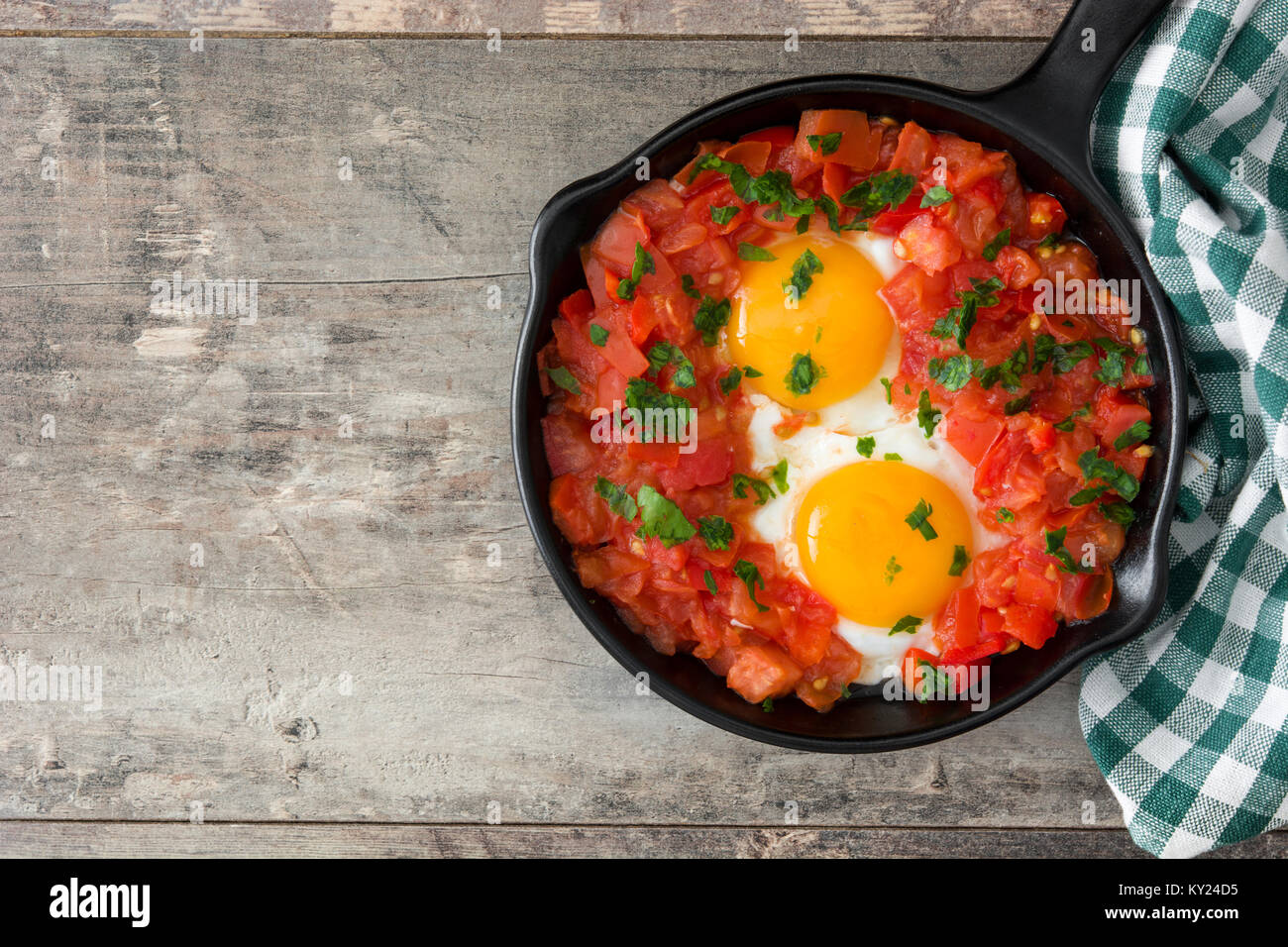 Shakshuka in iron frying pan on wooden table top view. Typical food in ...