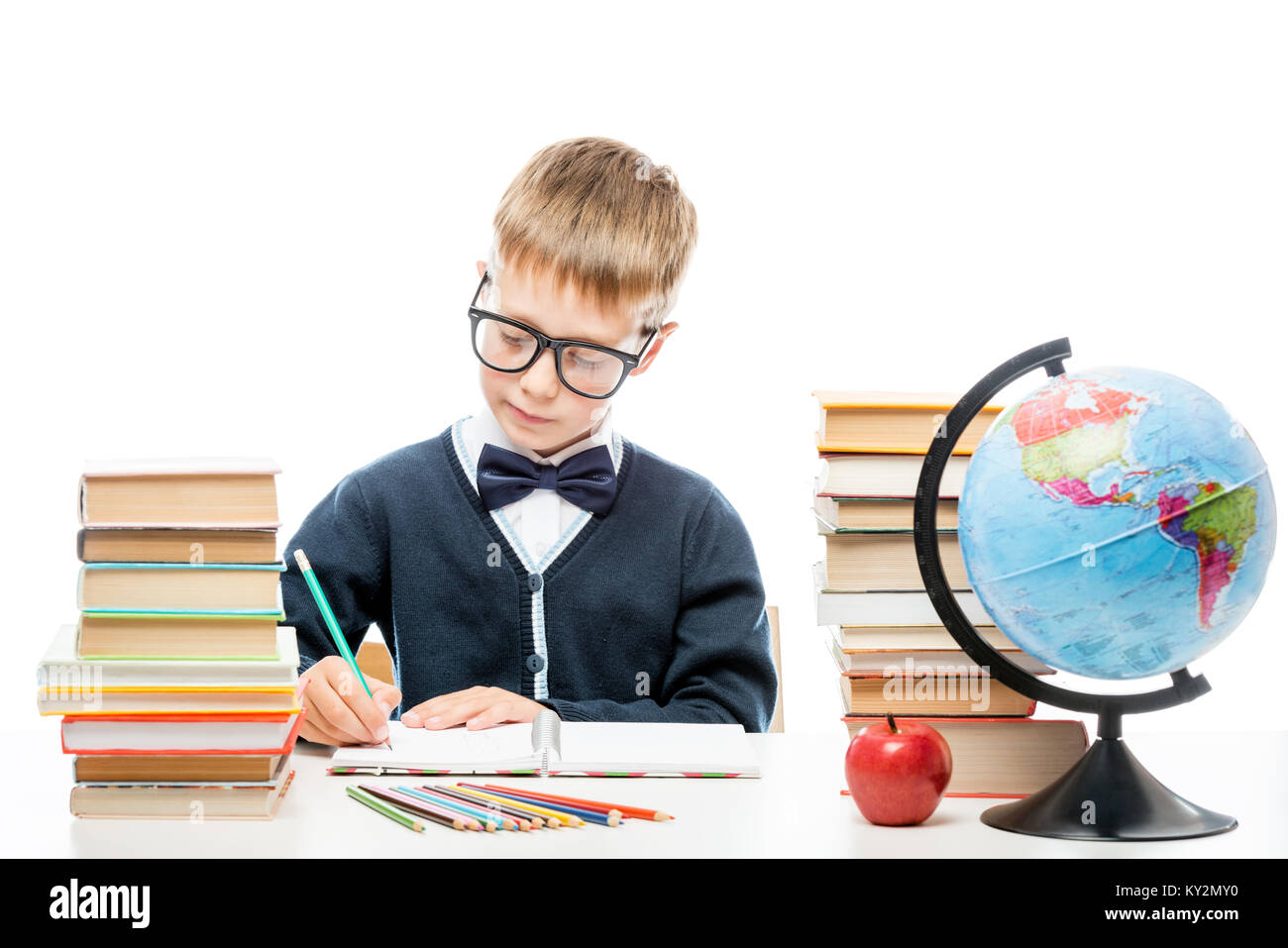 very smart schoolboy with glasses with books at the table on a white ...