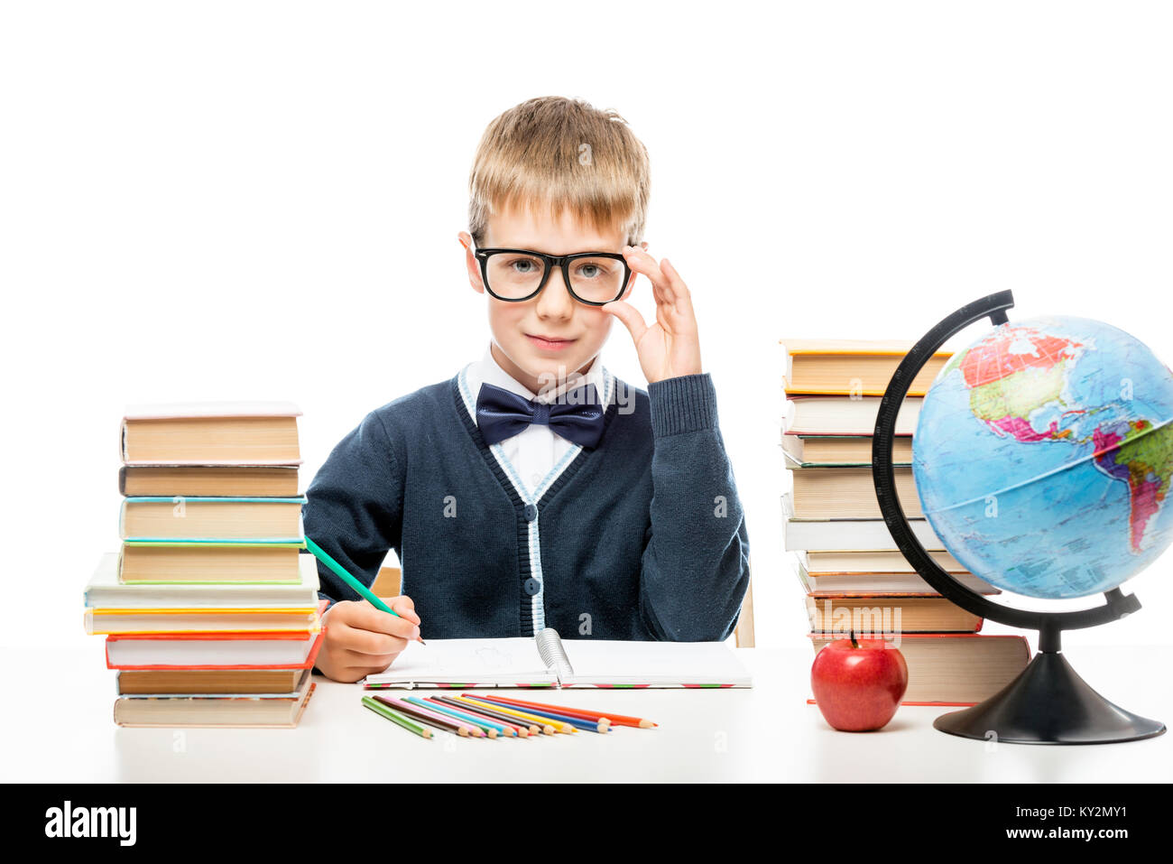 portrait of a happy smart schoolboy at the table with books on a white ...