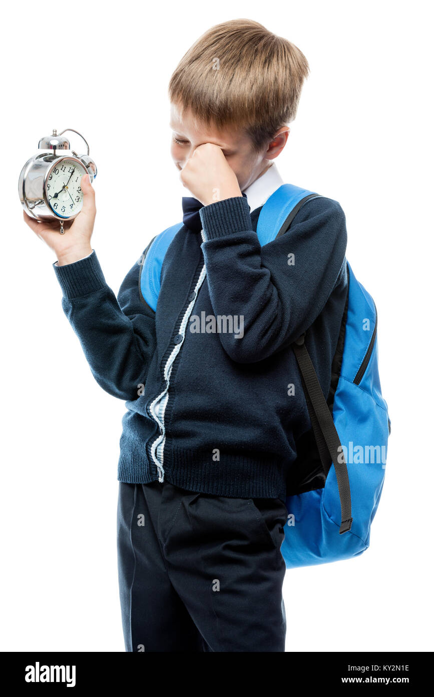 crying little boy in school uniform with an alarm clock on white ...