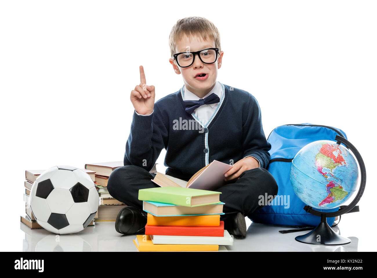 very smart boy with books, globe and soccer ball on white background ...