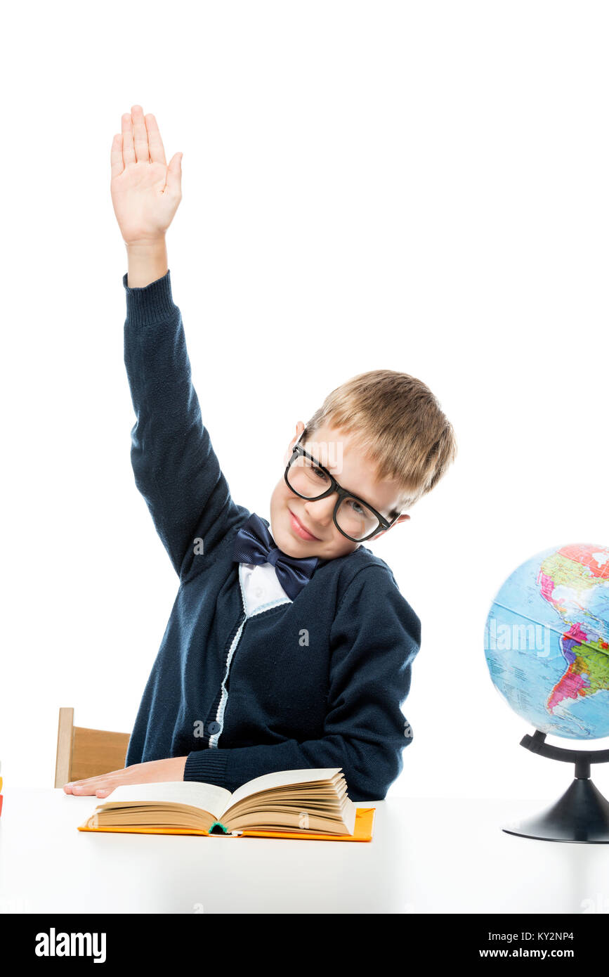 smart schoolboy pulls his arm while sitting at a desk Stock Photo - Alamy