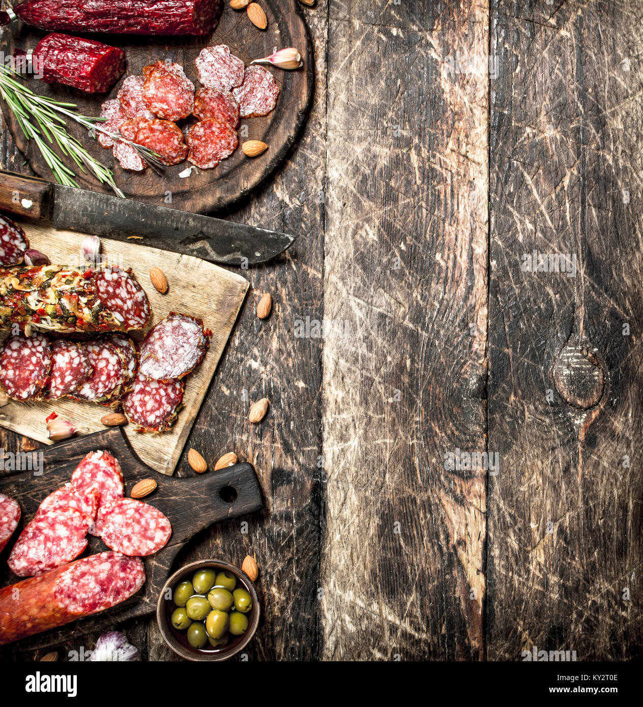 Different kinds of salami on the boards. On a wooden background Stock ...
