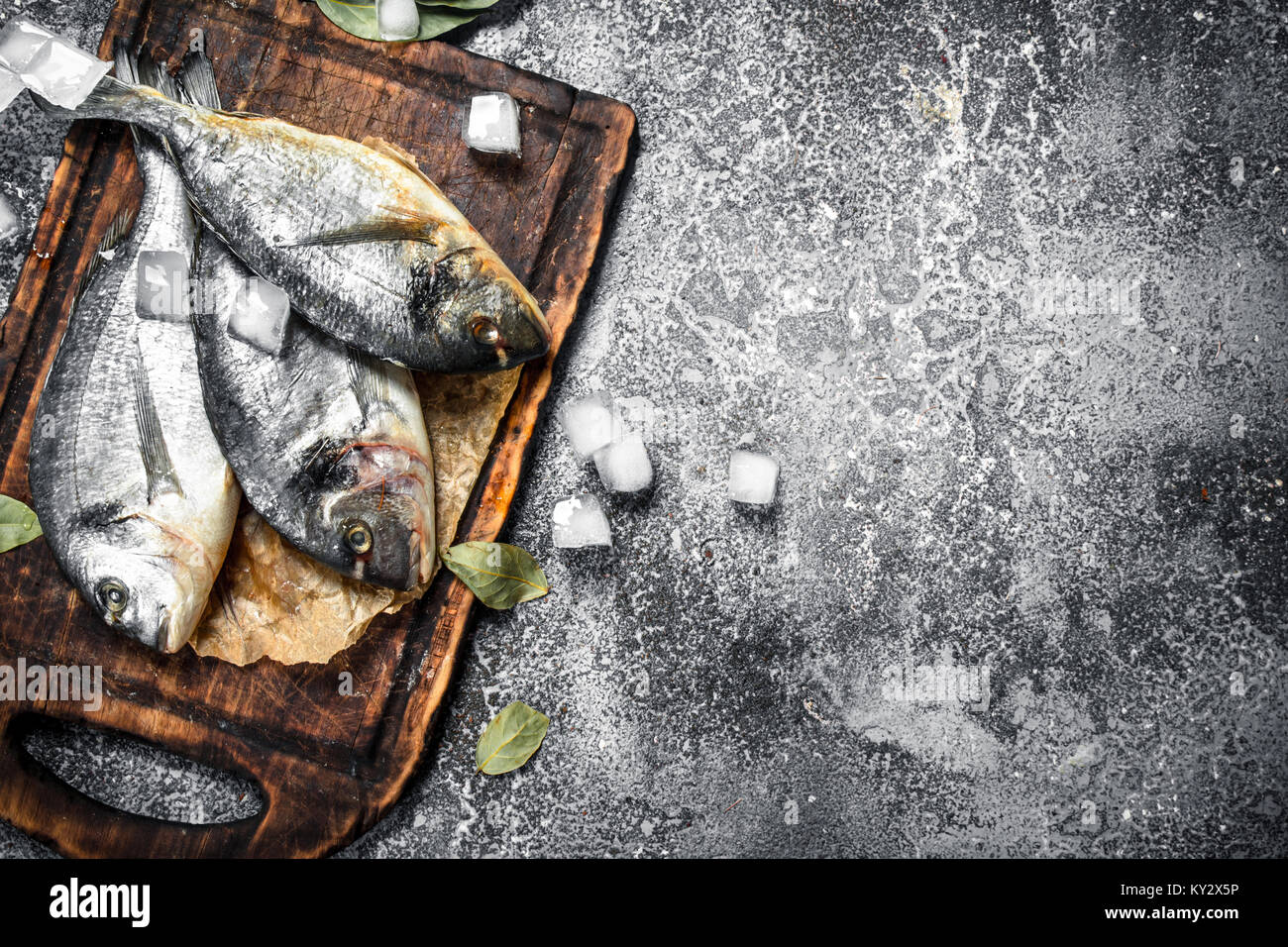 Fresh unprepared dorado fish on a cutting board. On a rustic background ...