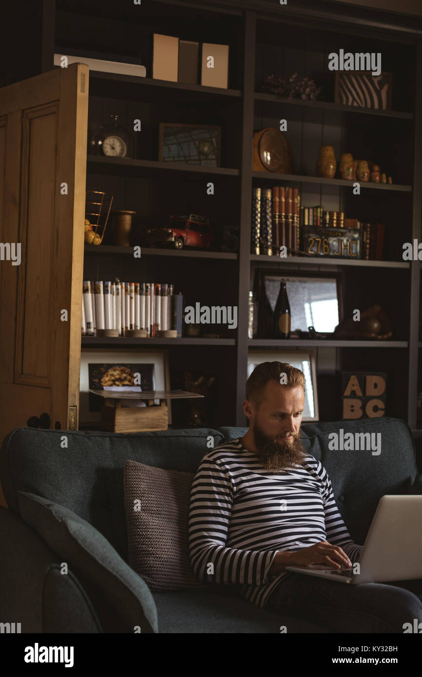 Man seating on sofa using his laptop Stock Photo - Alamy