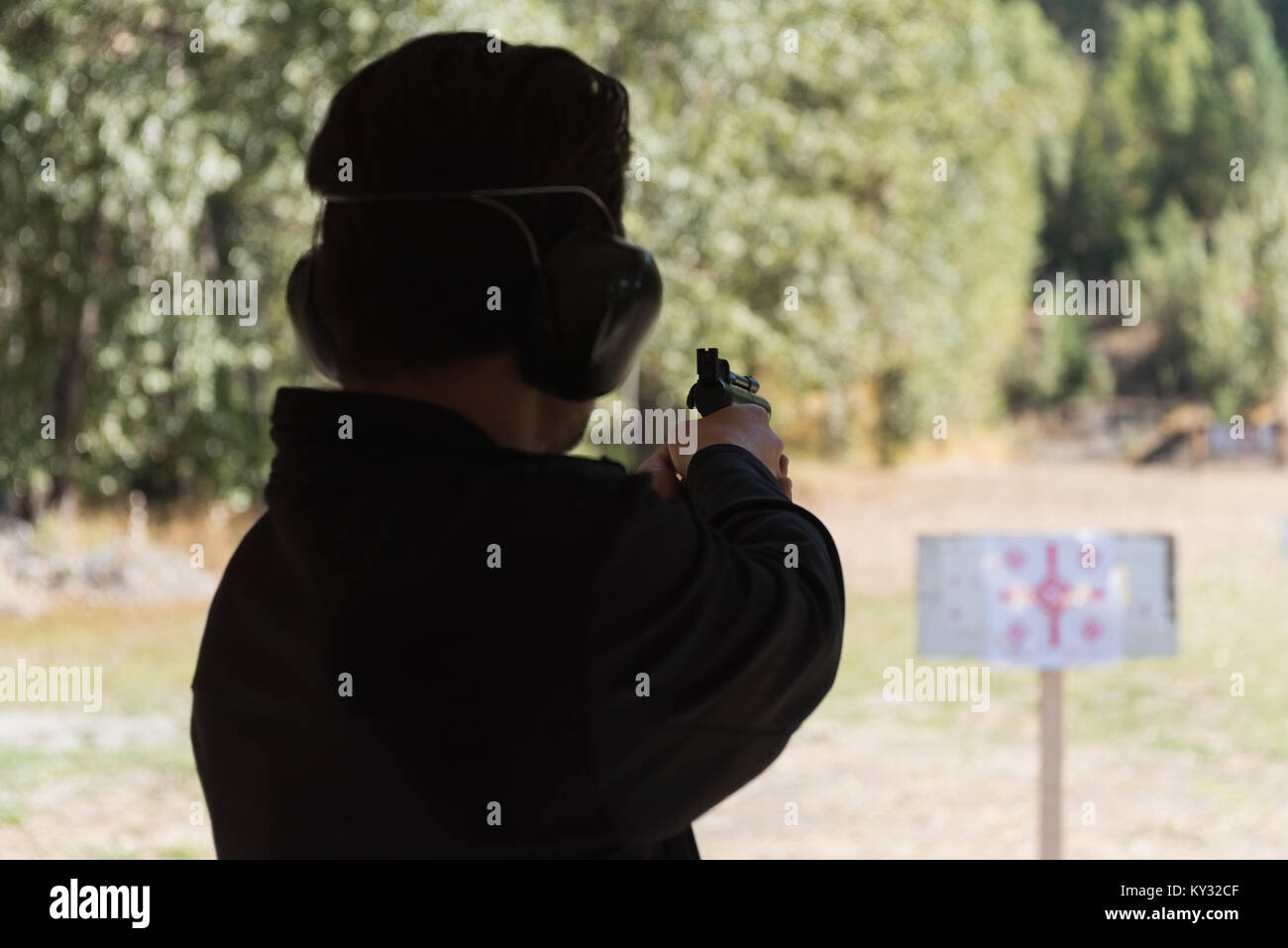 Man aiming gun at target in shooting range Stock Photo - Alamy